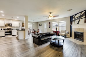 Uma sala de estar moderna com um sofá de couro preto, uma mesa de centro de vidro e uma lareira.