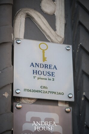 Placa para 'Andrea House' com símbolo de chave, indicando uma sala de piano, e um número de contato.