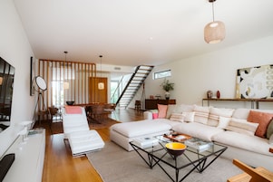 Uma sala de estar moderna com um sofá, mesa de centro e escada para um andar superior.