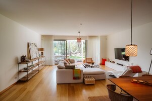 Uma sala de estar moderna com um sofá, uma mesa de jantar e uma televisão.