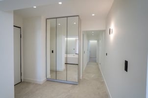 Um corredor com guarda-roupa espelhado, um interruptor de luz e uma porta.