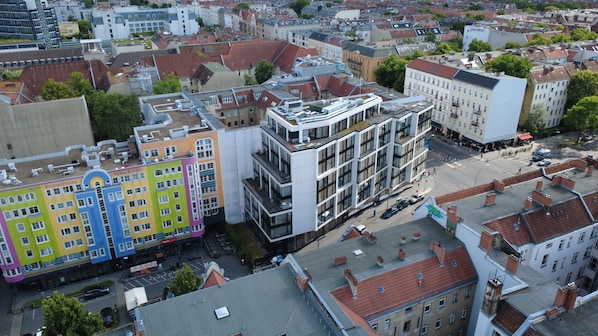 Um edifício de vários andares com telhado plano, rodeado por outros edifícios.
