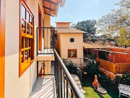Um edifício residencial com varanda, um pequeno jardim e uma estátua.