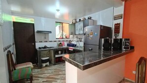 Uma cozinha com bancada de mármore, geladeira, fogão e pia.