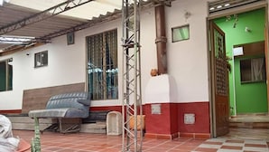 Um edifício residencial com um pátio ladrilhado, um sofá azul e uma porta verde.
