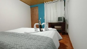 Quarto com uma cama, televisão e uma garrafa de champanhe.