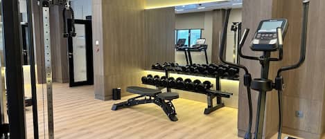 Uma academia com equipamentos de musculação, esteiras e halteres.