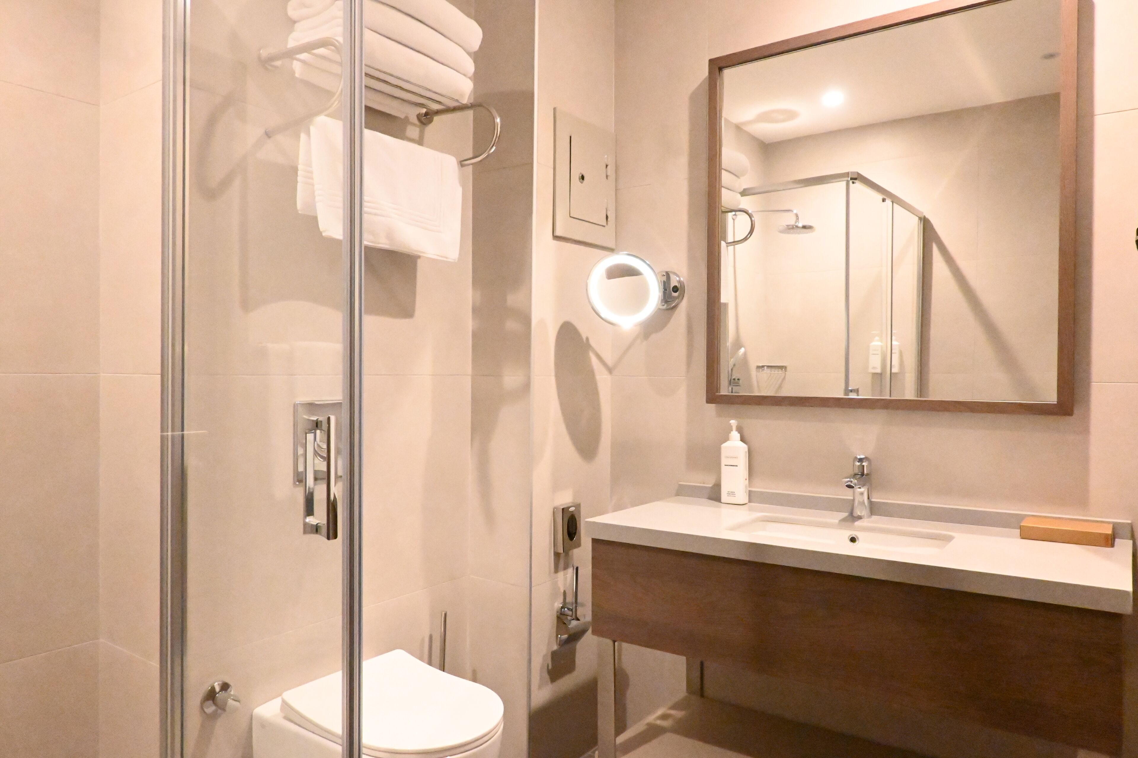 Um banheiro moderno com box de vidro, vaso sanitário, pia com espelho e porta-toalhas.