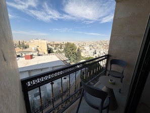Uma varanda com vista para um horizonte urbano, incluindo edifícios e árvores.