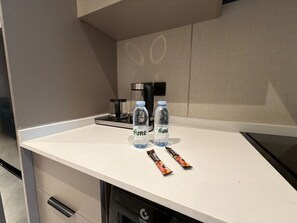 Uma bancada de cozinha com duas garrafas de água, uma cafeteira e duas barras de chocolate.