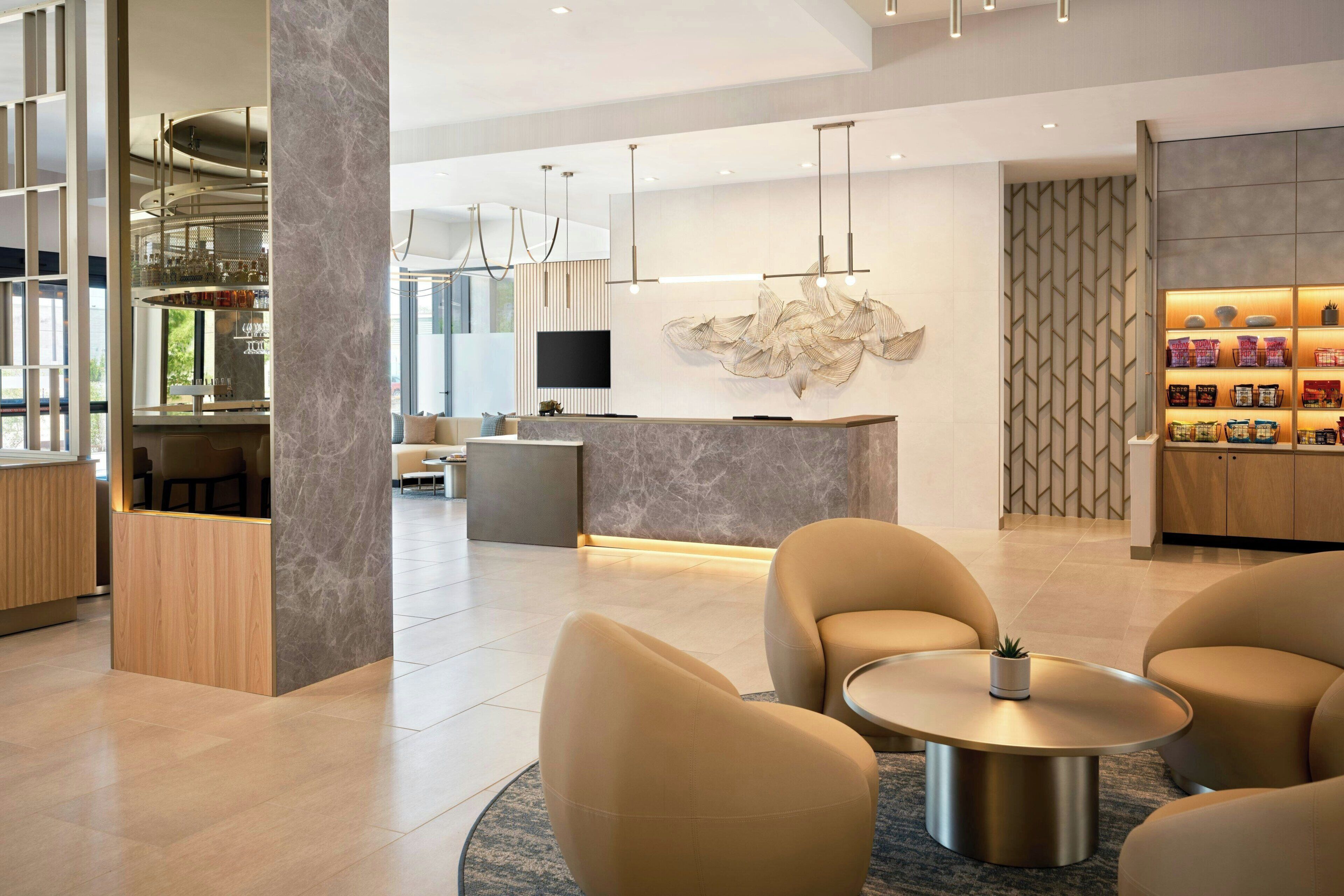 Um hall de hotel moderno com área de bar, assentos e uma parede decorativa.