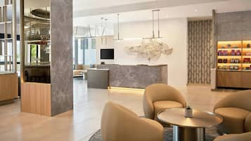 Um hall de hotel moderno com área de bar, assentos e uma parede decorativa.