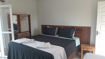 Quarto com cama, cabeceira de madeira, mesa de cabeceira e espelho.