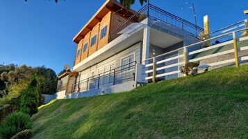 Um edifício de dois andares com varanda, garagem e um declive gramado.