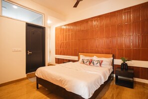 Um quarto com uma cama, uma cabeceira de madeira, uma mesa de cabeceira e uma porta.