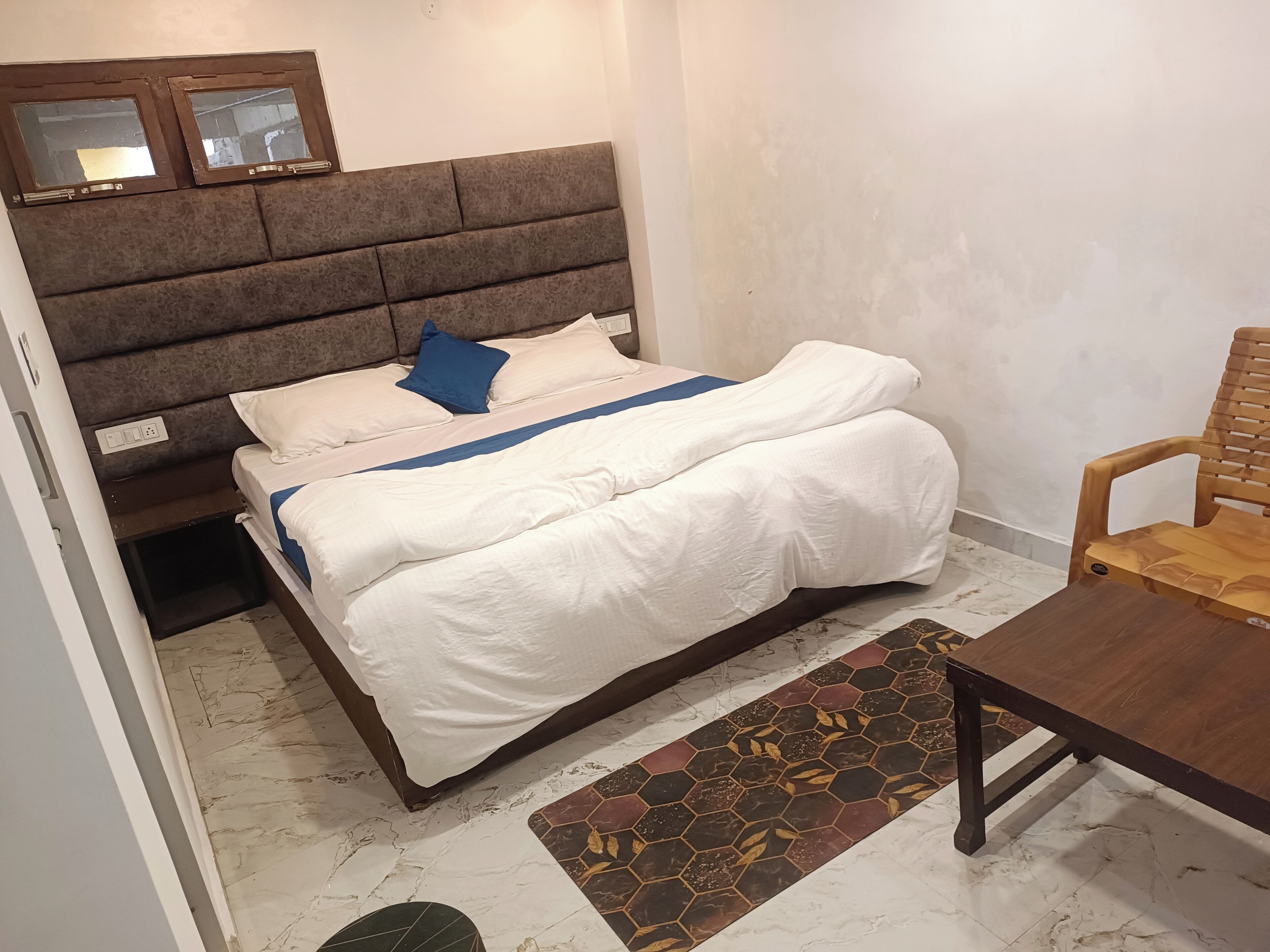 Uma cama com cabeceira, mesa de cabeceira e uma cadeira.