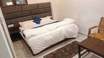 Uma cama com cabeceira, mesa de cabeceira e uma cadeira.