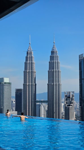 Vista das Torres Petronas a partir de uma piscina com água azul cristalina.