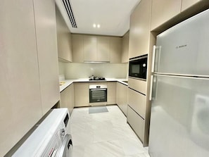 Cozinha compacta com geladeira Bosch, forno e micro-ondas, além de máquina de lavar.