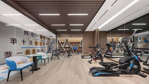 Academia moderna com equipamentos de ginástica, área de estar e parede com mensagens motivacionais.