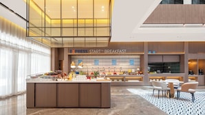Uma área de café da manhã moderna com ilha central, assentos e uma placa com a inscrição 'EXPRESS START BREAKFAST'.