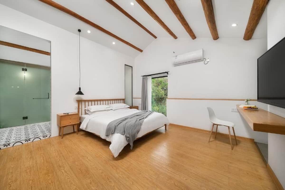 Quarto moderno com teto de madeira, uma cama, uma escrivaninha e uma cadeira.
