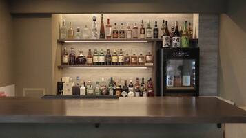 Uma área de bar com várias prateleiras de garrafas de bebidas, um relógio digital e uma geladeira.