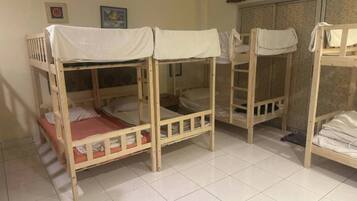 Quarto com beliches, piso ladrilhado, guarda-roupa e um quadro na parede.