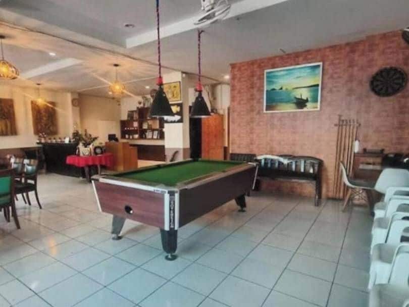 Uma sala de jogos com mesa de bilhar, cadeiras e alvo de dardos.