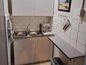 Uma cozinha compacta com pia dupla, bancada pequena e painel de azulejos.
