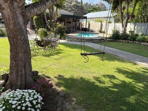 Um quintal com balanço, piscina e gramado.