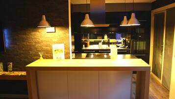 Uma cozinha moderna com iluminação pendente, uma ilha central e painel de pedra.