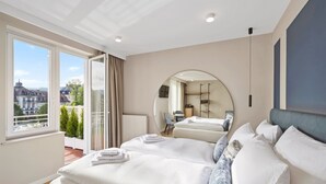 Quarto de hotel com uma cama grande, varanda com vista, espelho redondo e escrivaninha com cadeira.