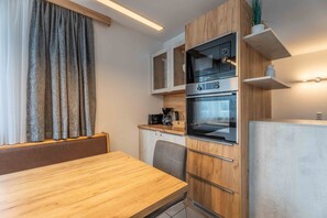 Uma cozinha moderna com armários de madeira, forno embutido e área de refeições com mesa e banco de madeira.