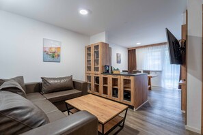 Uma sala de estar moderna com sofá, mesa de centro, armário de madeira e uma área de cozinha com mesa de jantar.