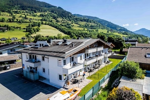 Um hotel moderno com vários andares, área externa para sentar e vista para colinas verdes.