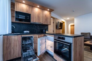 Uma cozinha moderna com armários de madeira, eletrodomésticos embutidos e uma bancada de mármore preto.