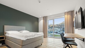 Quarto de hotel com cama, escrivaninha e cadeira.