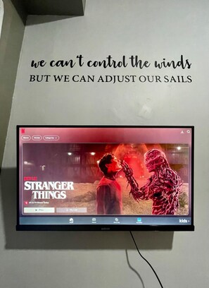 Uma TV exibindo 'Stranger Things' na Netflix, com uma frase motivacional acima.