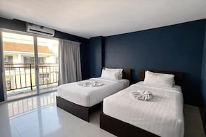 Quarto de hotel com duas camas, varanda e vista, além de ar condicionado.