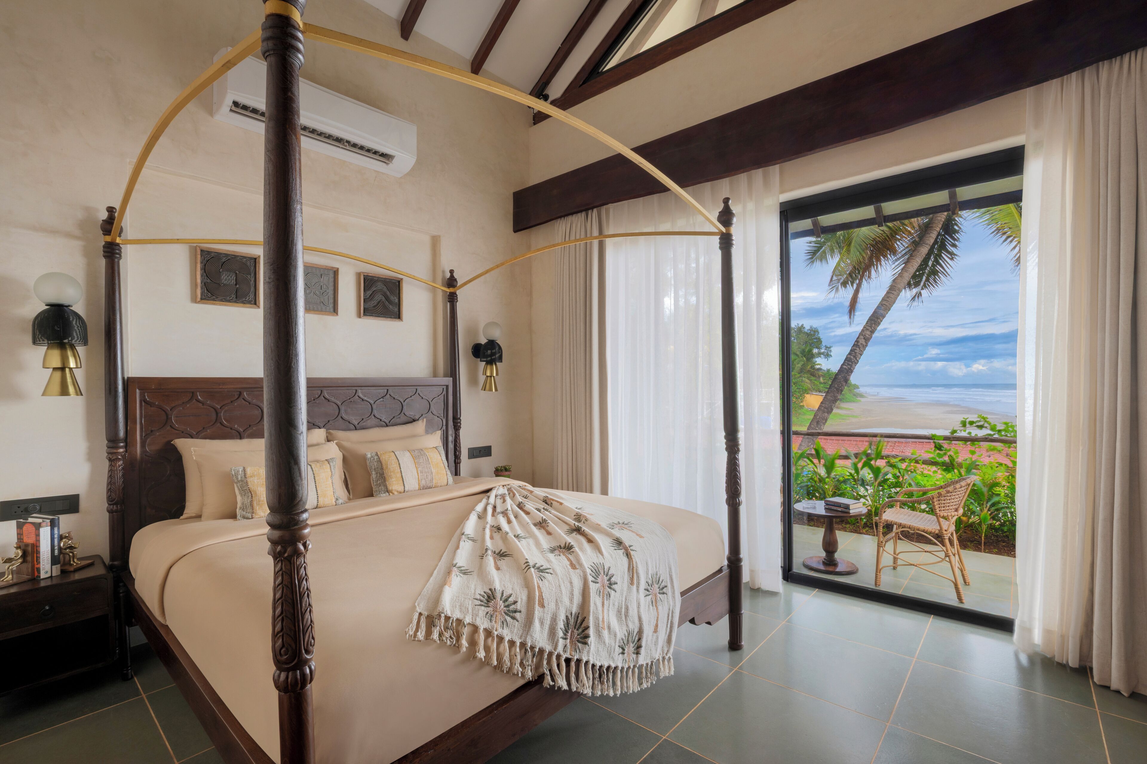 Uma cama com dossel com vista para a praia através de uma grande janela.
