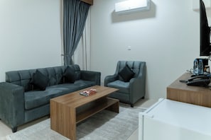 Uma sala de estar moderna com sofá, poltrona, mesa de centro e televisão de tela plana.