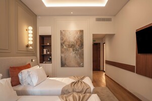 Quarto de hotel com cama, mesa de cabeceira, luminária, obra de arte e televisão.