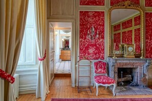 Um quarto com lareira, um espelho e uma cadeira.