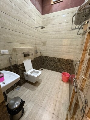 Casa de banho com sanita, lavatório, chuveiro e esfregão.