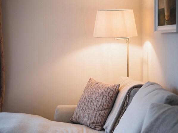 Quarto bem organizado com cama, almofadas, abajur e um quadro na parede.