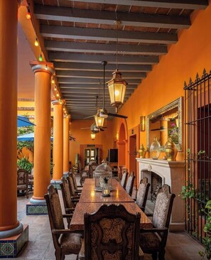 Uma sala de jantar com uma mesa comprida, cadeiras e lareira.