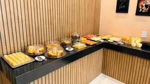 Um balcão de buffet com diversos alimentos e uma parede revestida de madeira.