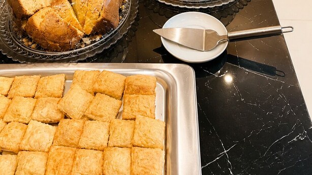 Buffet com diversos alimentos, incluindo pão, doces e frutas.