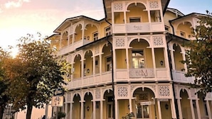 Um edifício com vários andares, varandas, janelas em arco e uma placa indicando um restaurante.